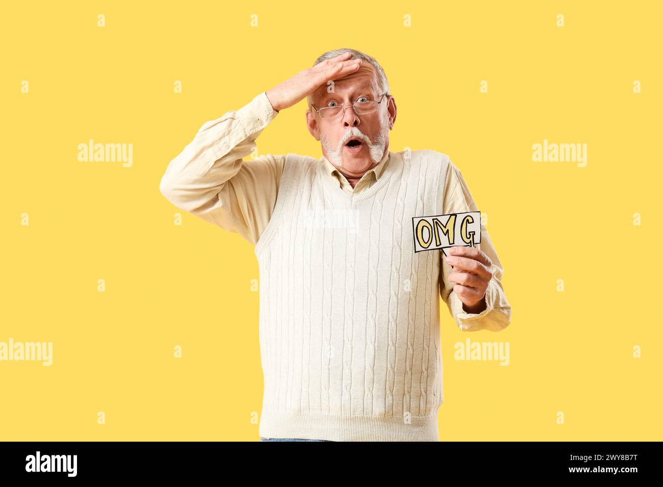 Shocked senior man holding speech bubble with word OMG on yellow ...