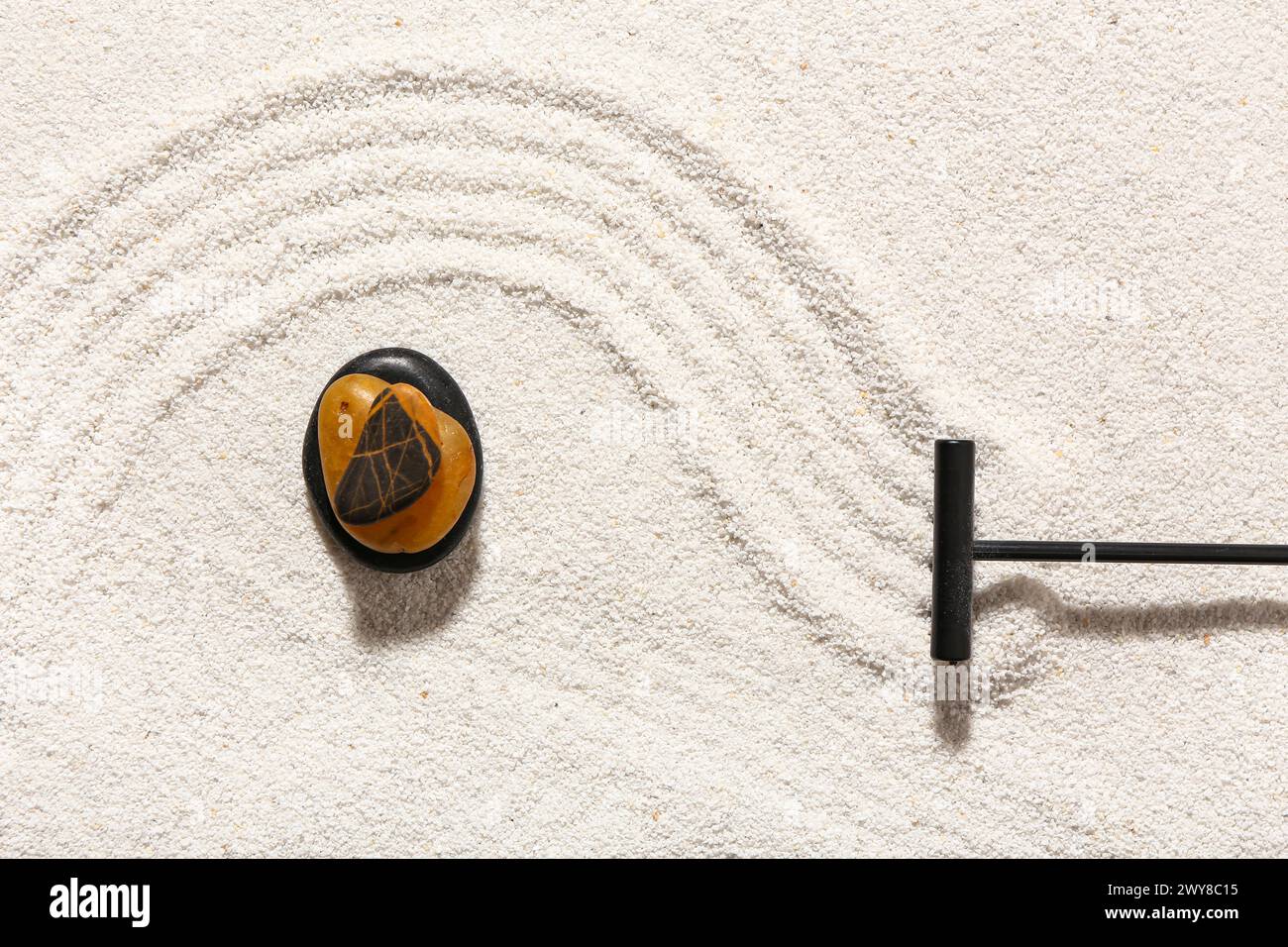 Rake and stones on sand with lines in Japanese rock garden. Zen concept ...