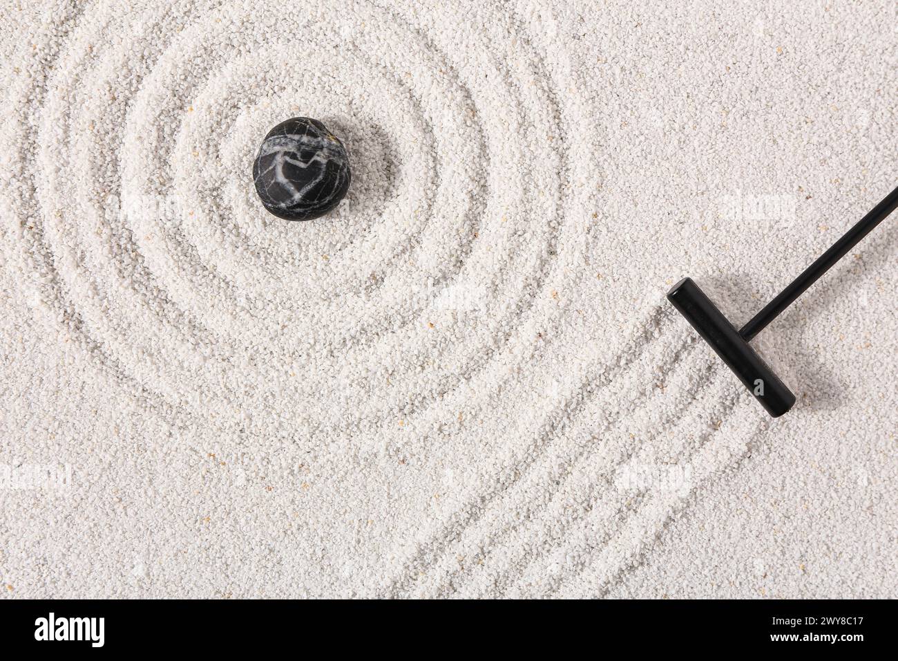 Rake and stone on sand with lines in Japanese rock garden, top view ...
