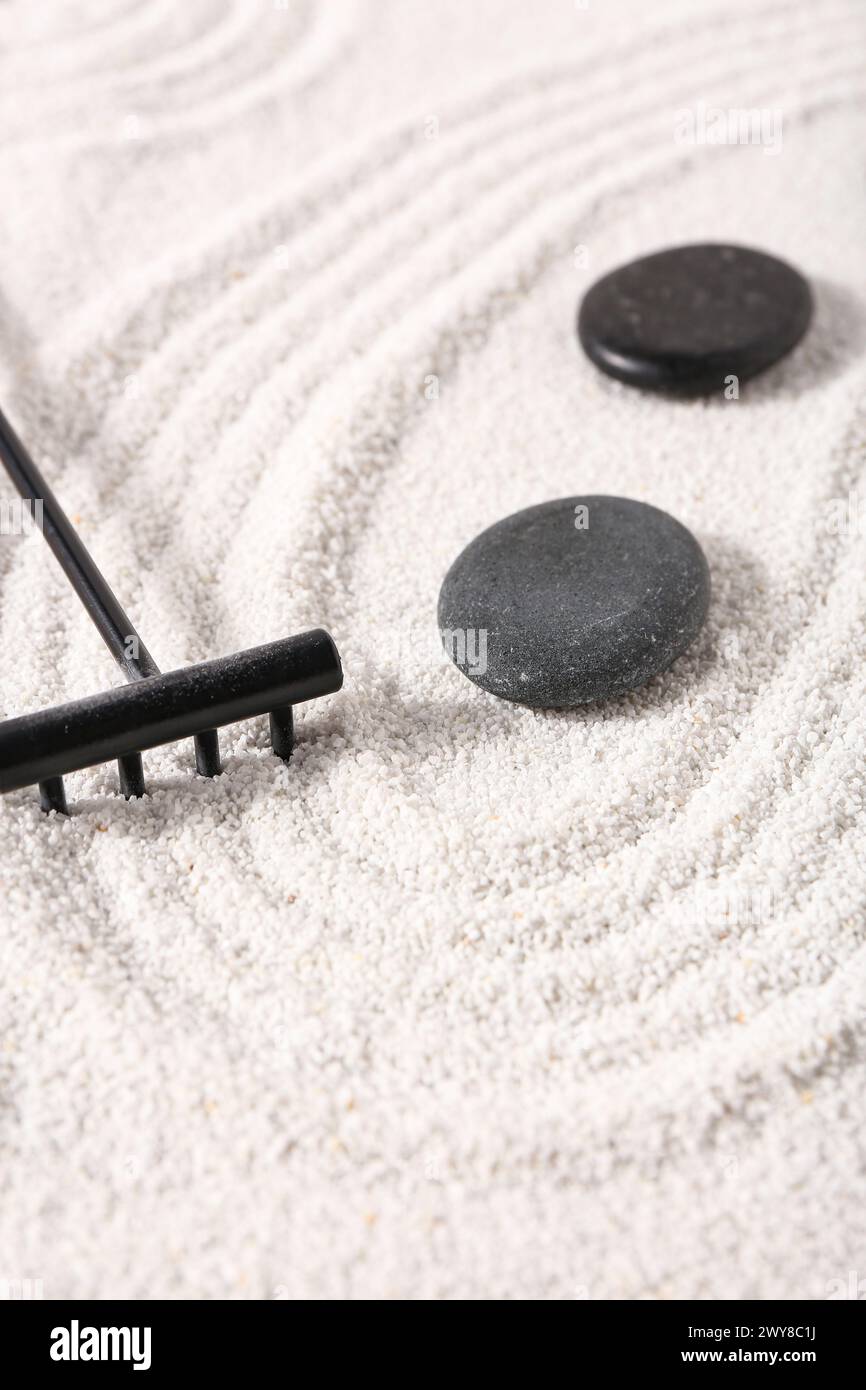 Rake and stones on sand with lines in Japanese rock garden. Zen concept ...