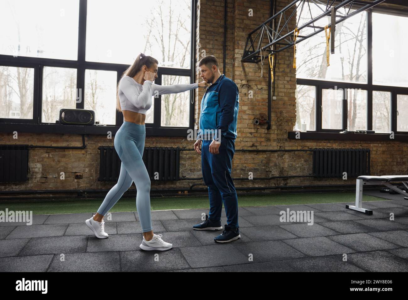 Young woman improving fighting skills with personal instructor at gym ...