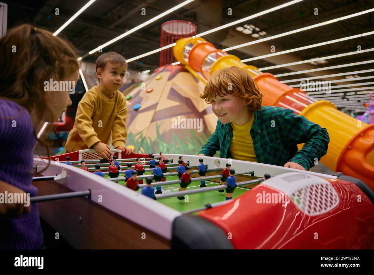 Happy excited children playing table football at entertainment center ...
