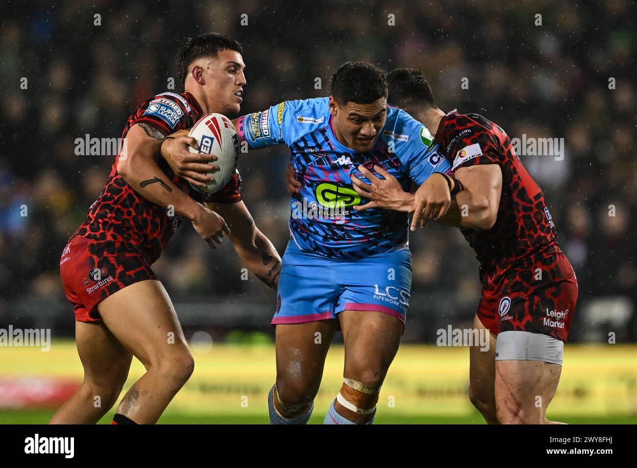 Patrick Mago of Wigan Warriors is tackled by Owen Trout of Leigh ...