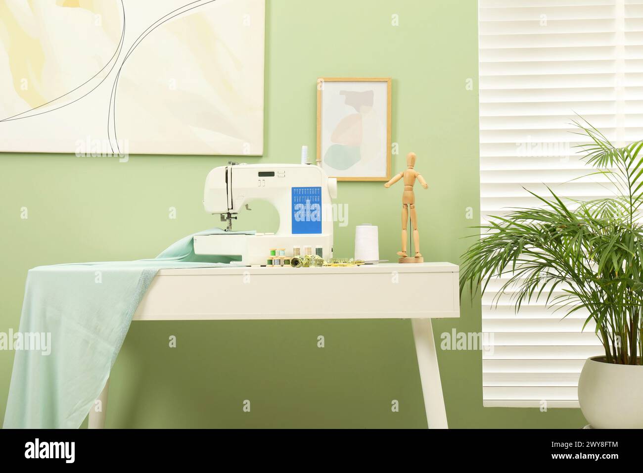 Modern sewing machine with cloth and craft accessories on white table ...