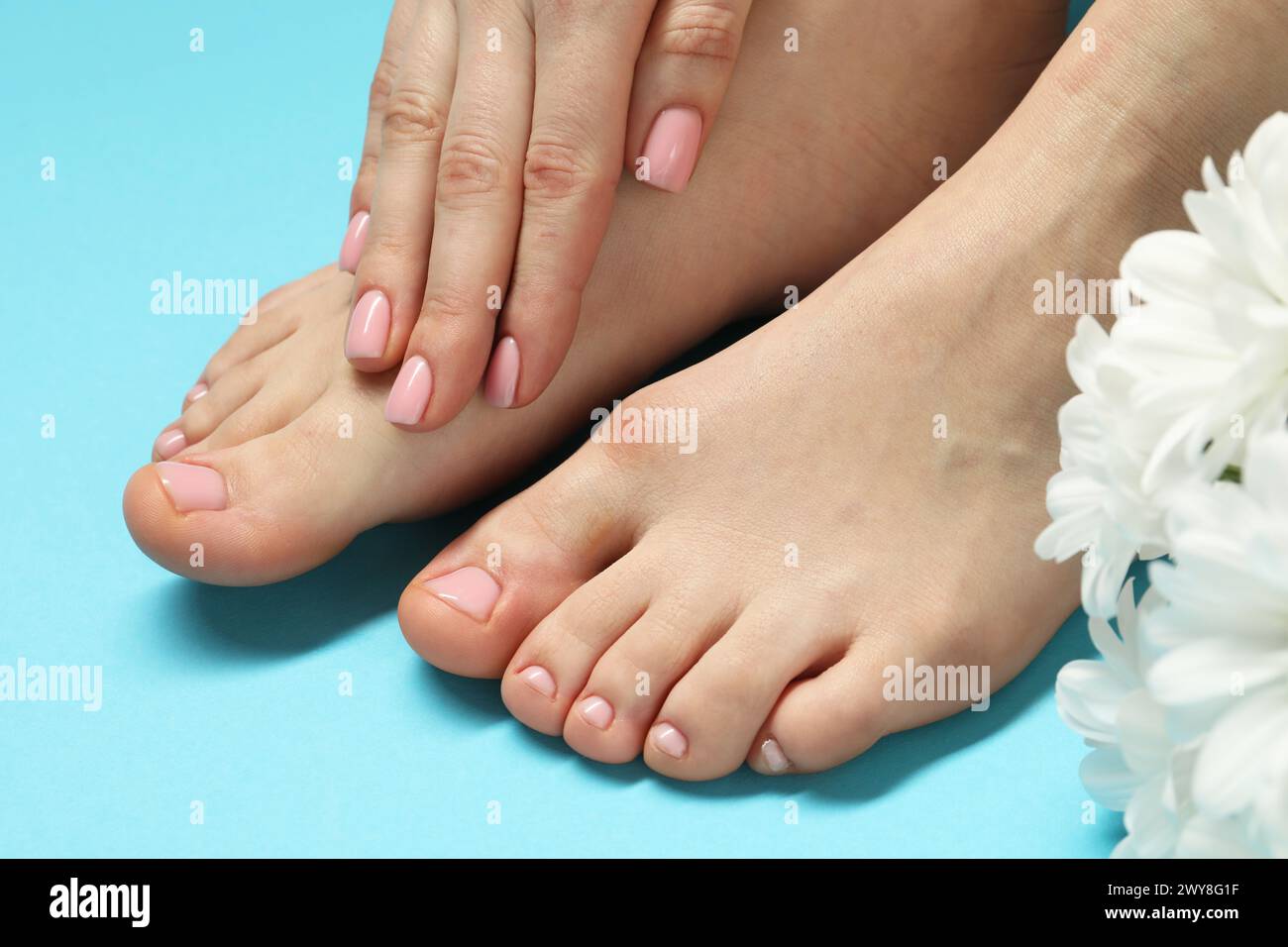 Woman with neat toenails after pedicure procedure on light blue ...