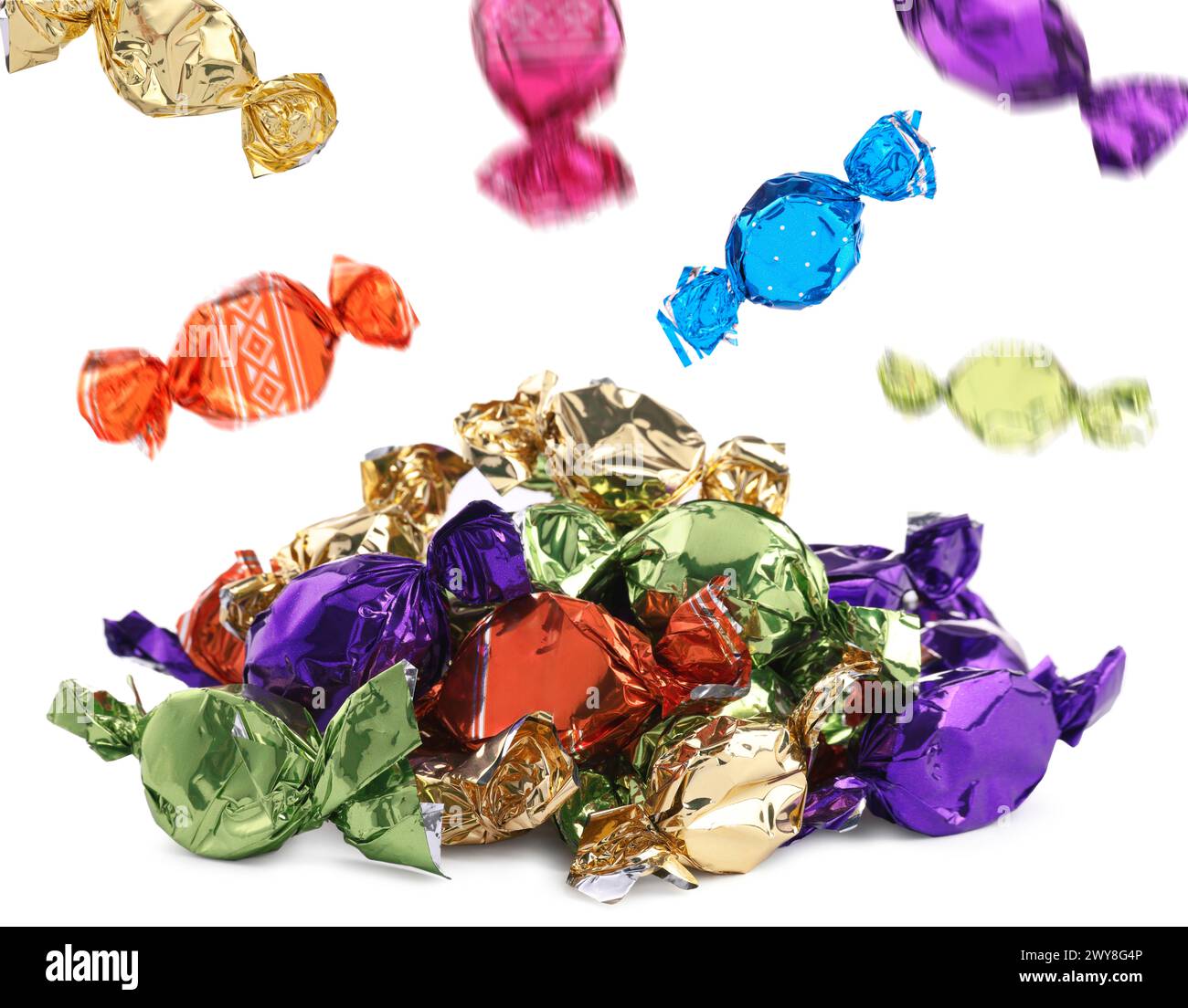 Candies in bright wrappers falling onto heap against white background ...