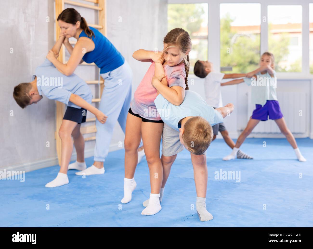 Kids in sportswear exercising self-protection techniques in pair during ...
