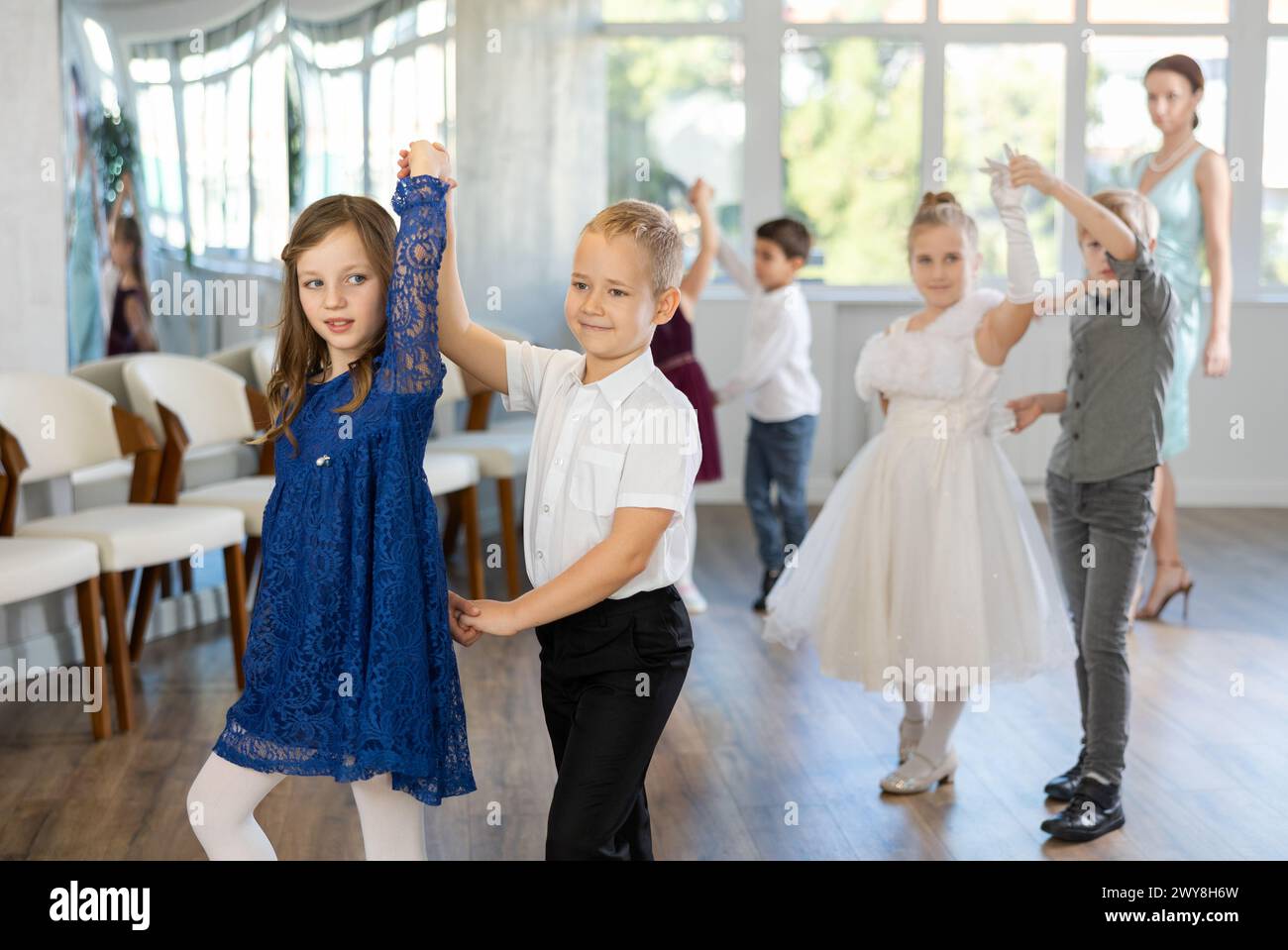 Enthusiastic preteen children dancing waltz in pairs in dance school ...