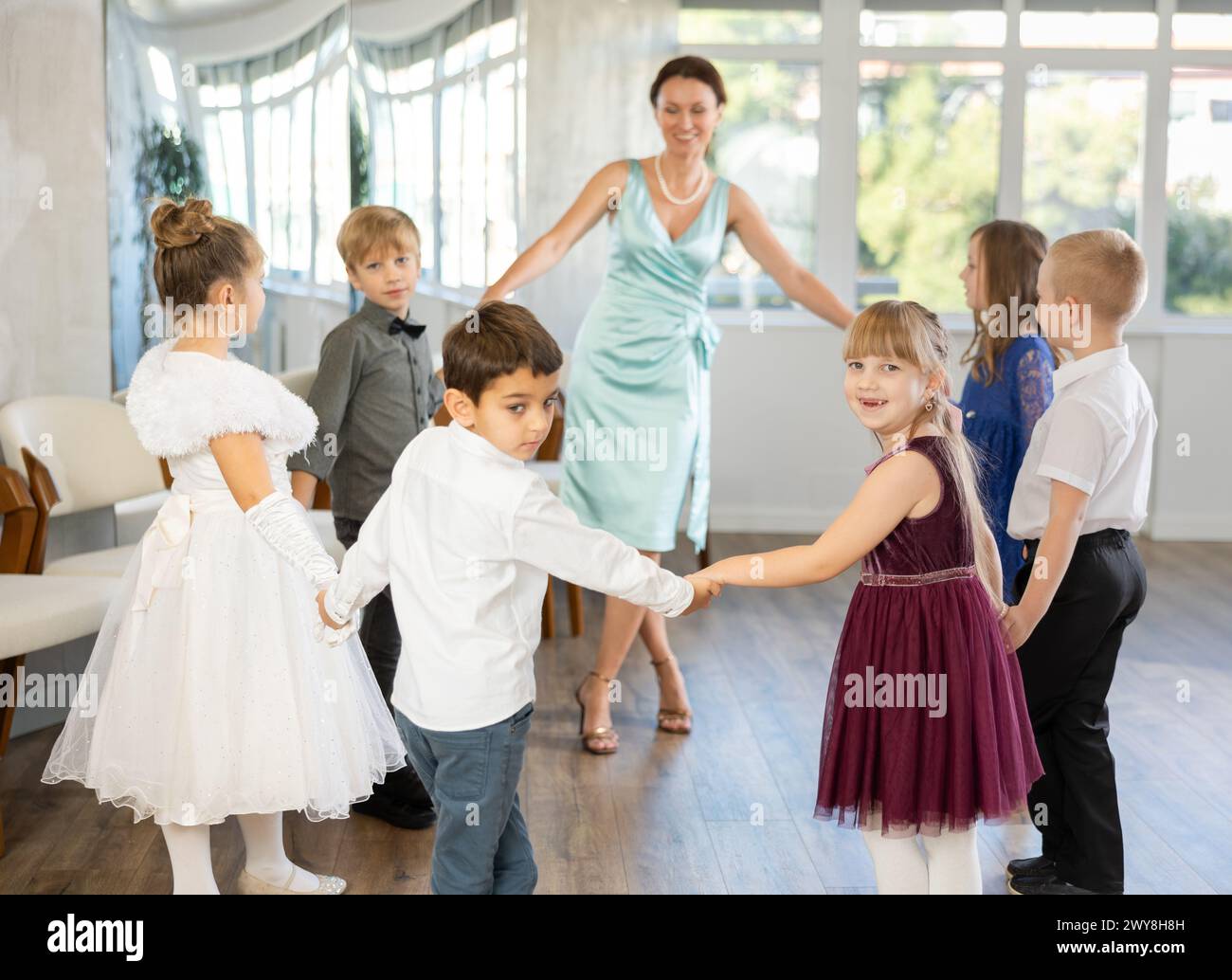 Class of preteen pupils learning circle dance with female teacher Stock ...