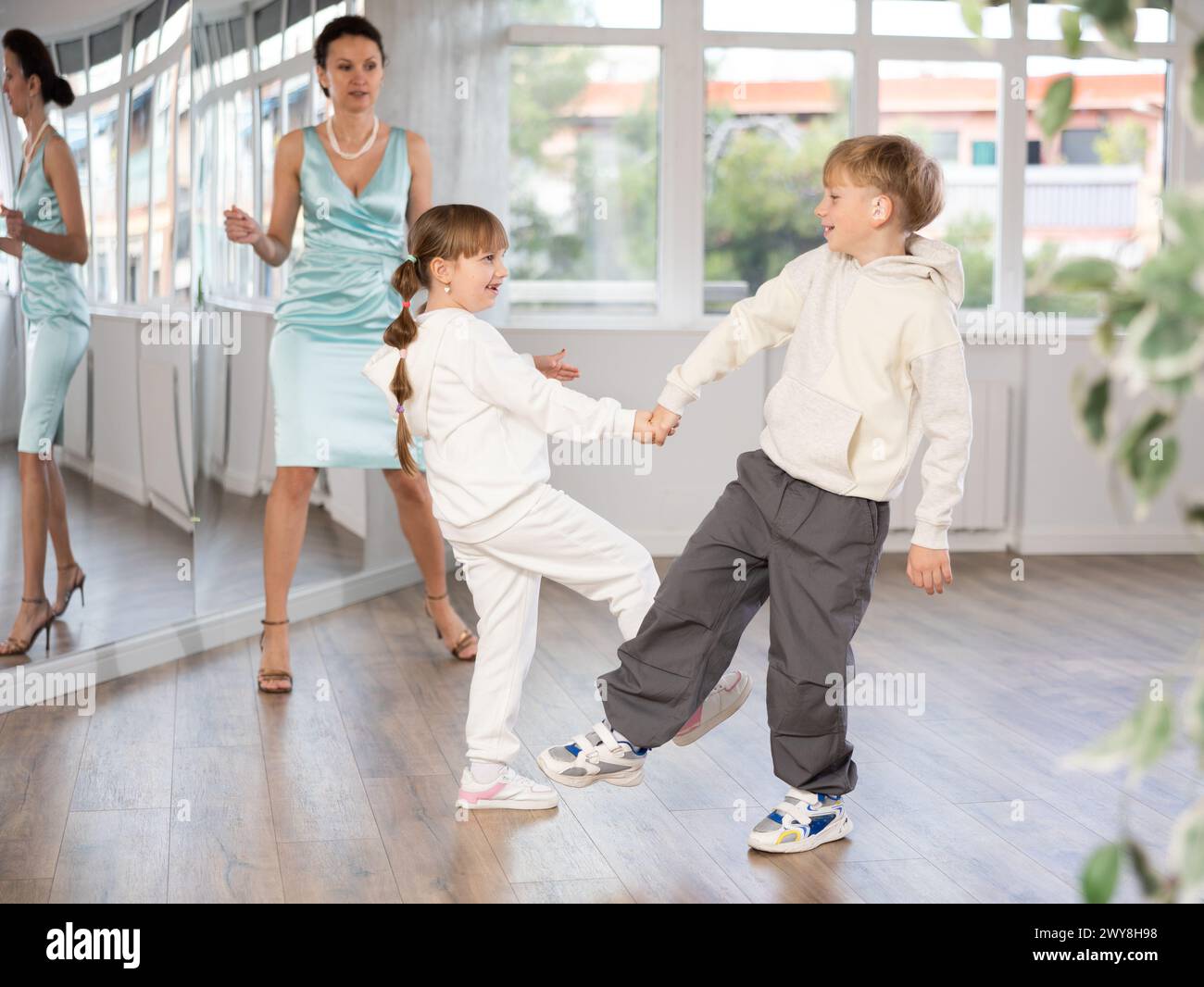 Cheerful tween girl and boy rehearsing jive in dance studio with ...