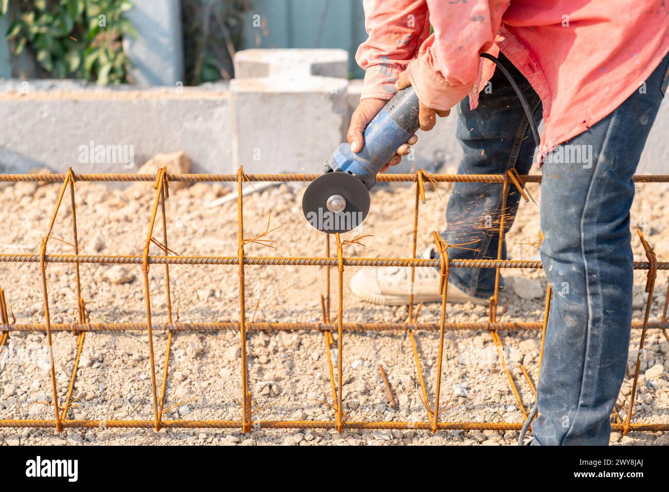 Worker hand cuts off pieces of reinforcement using an angle grinder in ...
