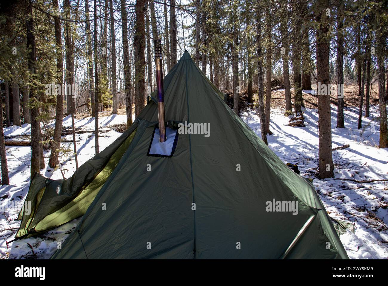 This image depicts a teepee tent set up in a snowy landscape, with a ...