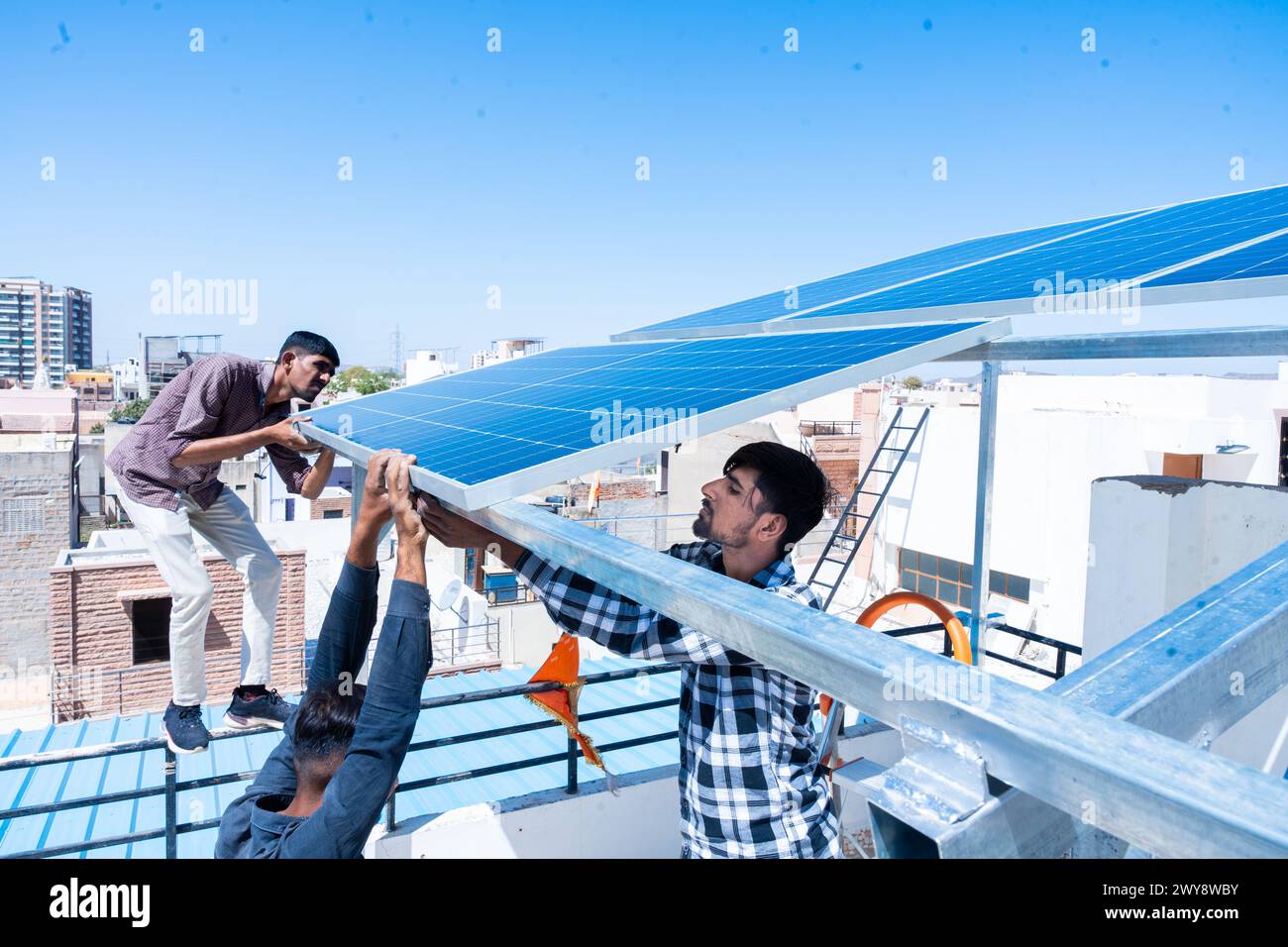 Indian workers installing solar panels on roof of house. Maintenance of ...