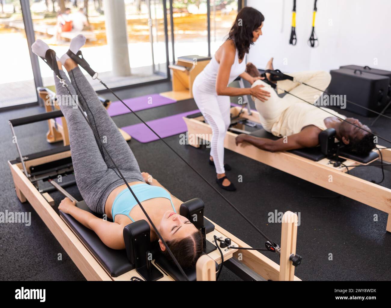 Female pilates trainer helping pilates people during training Stock ...