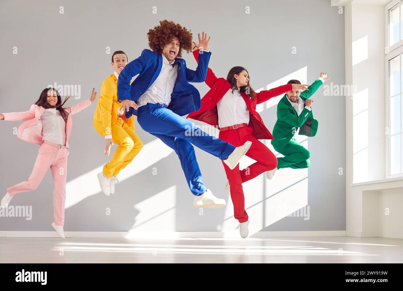 Dressed in colorful business suits group of dancers dancing and jumping ...