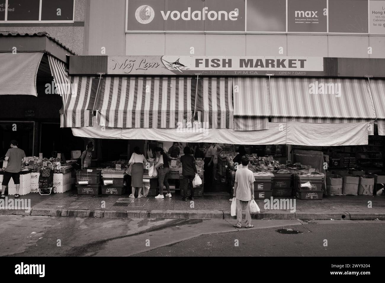 A man stands waiting on the road outside a Seafood fish market in ...