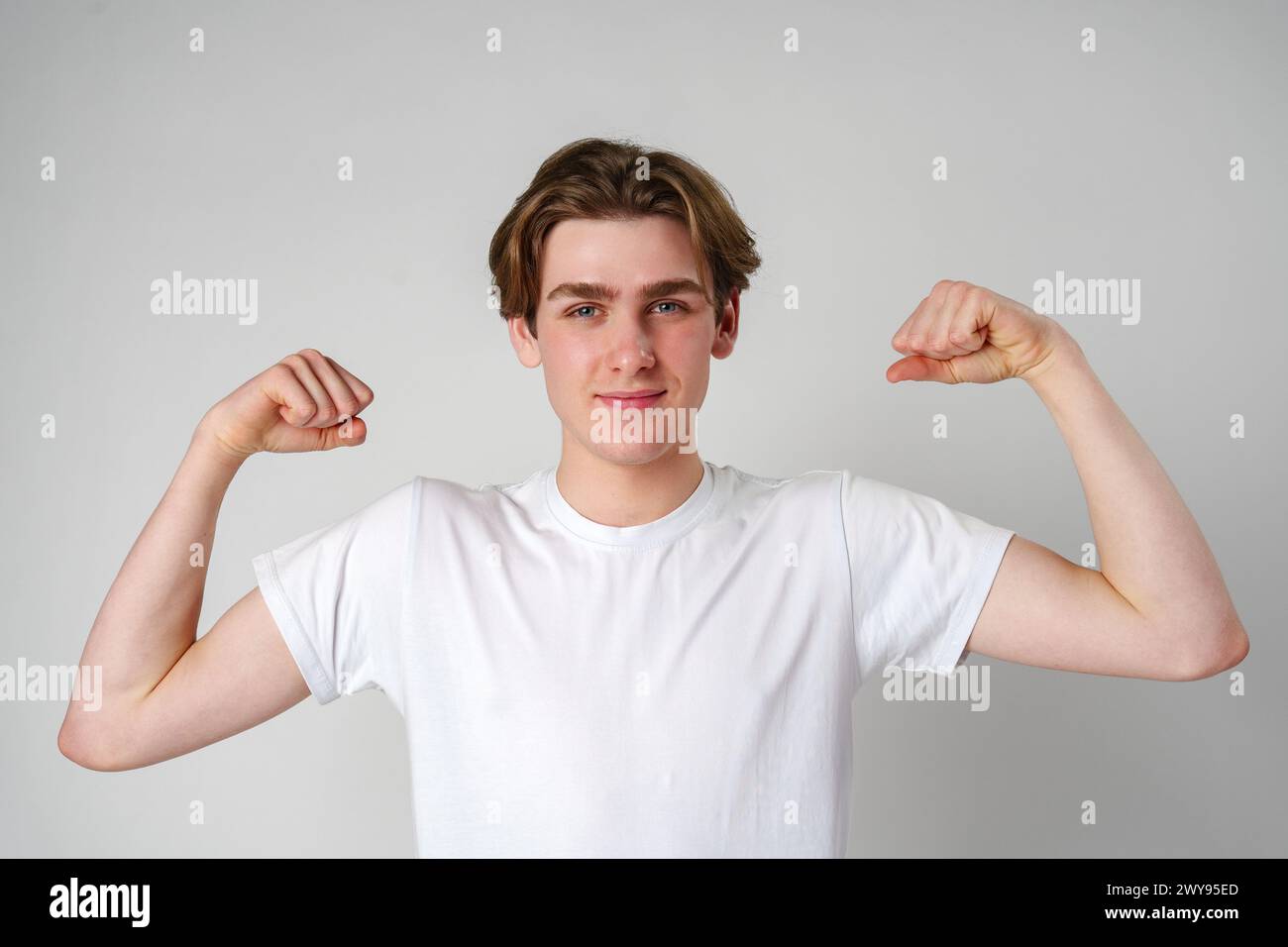 Young Man Flexing Muscles in Front of White Background Stock Photo - Alamy