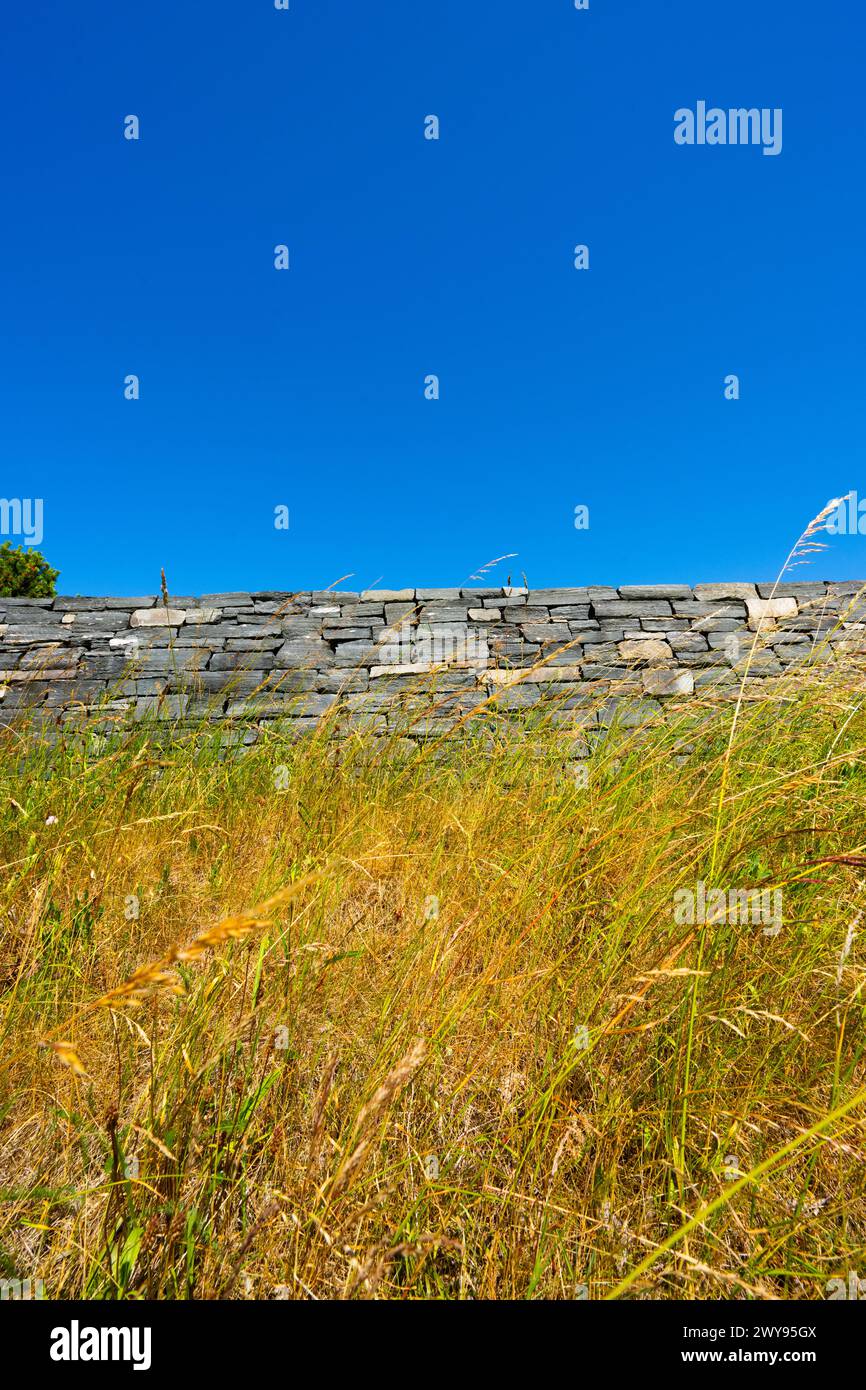 Rock wall on top of a grass incline Stock Photo - Alamy