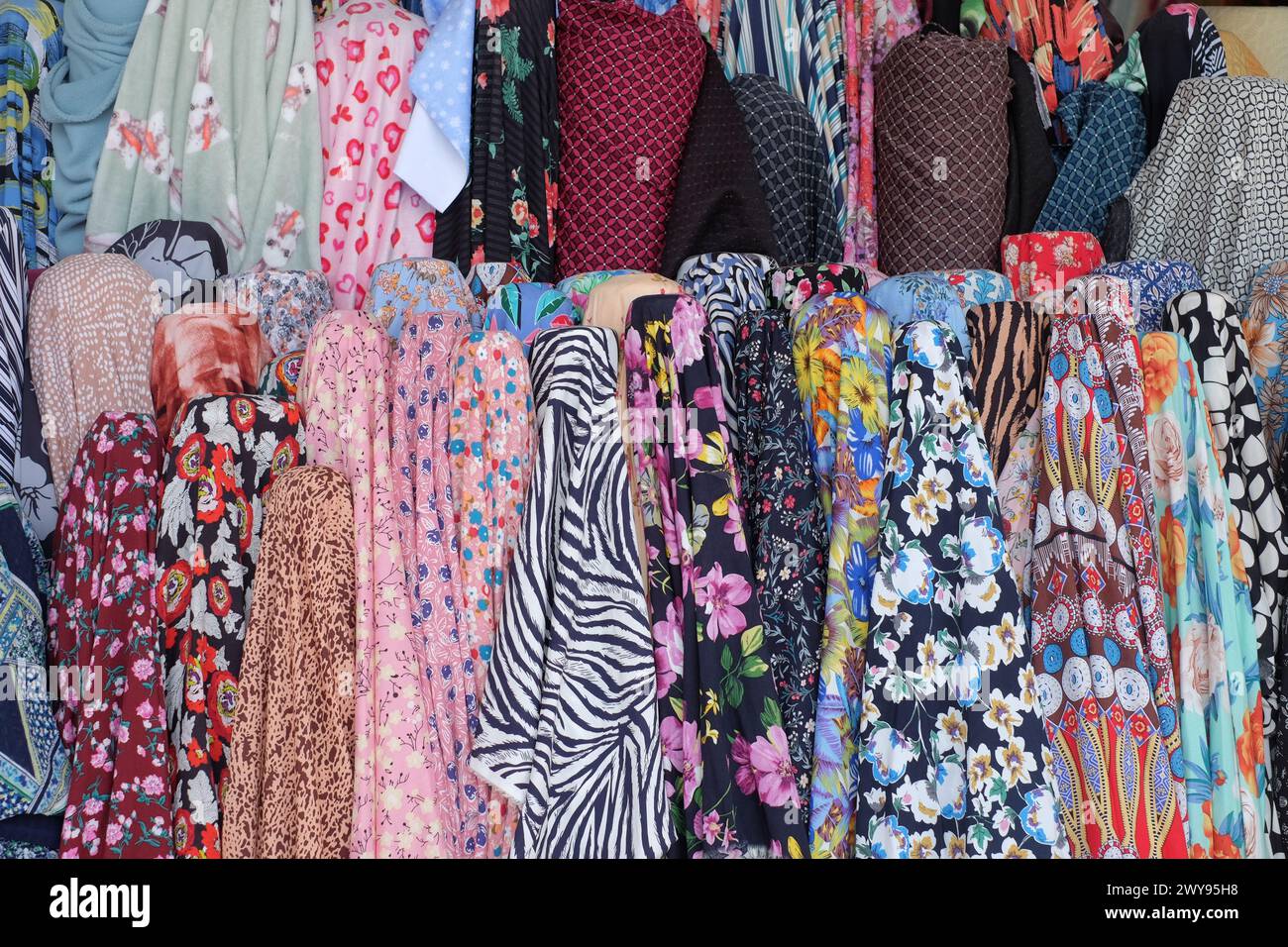 Colourful rolls of patterned fabric displayed in front of a dressmaking ...