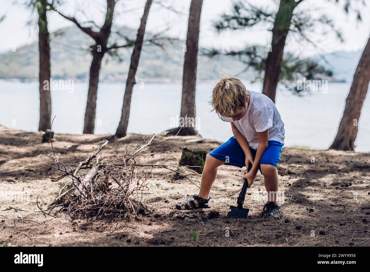 Cute boy digging soil in forest near sea beach. Family natural ...