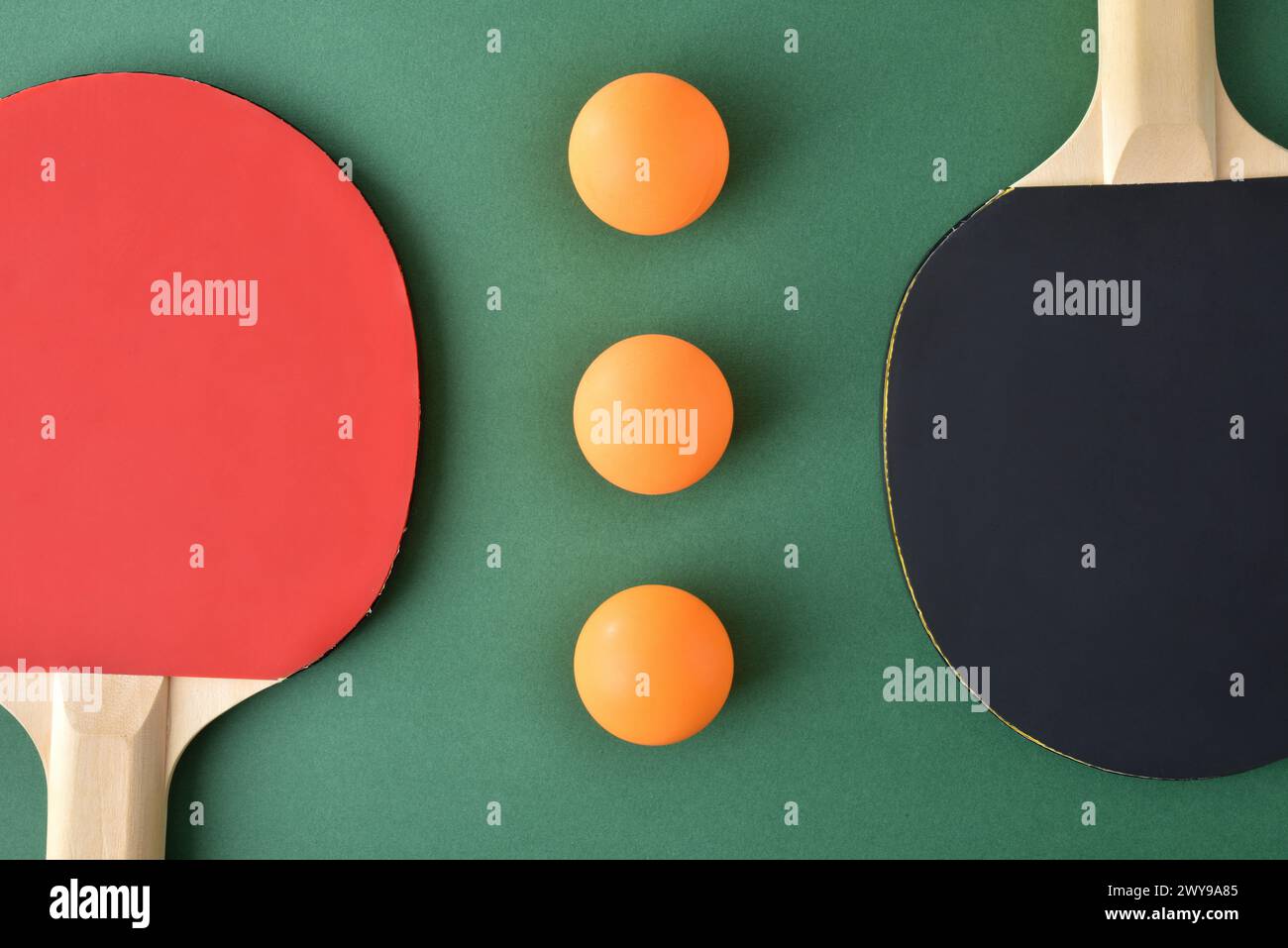 Composition with set of ping pong paddles and three orange balls on ...
