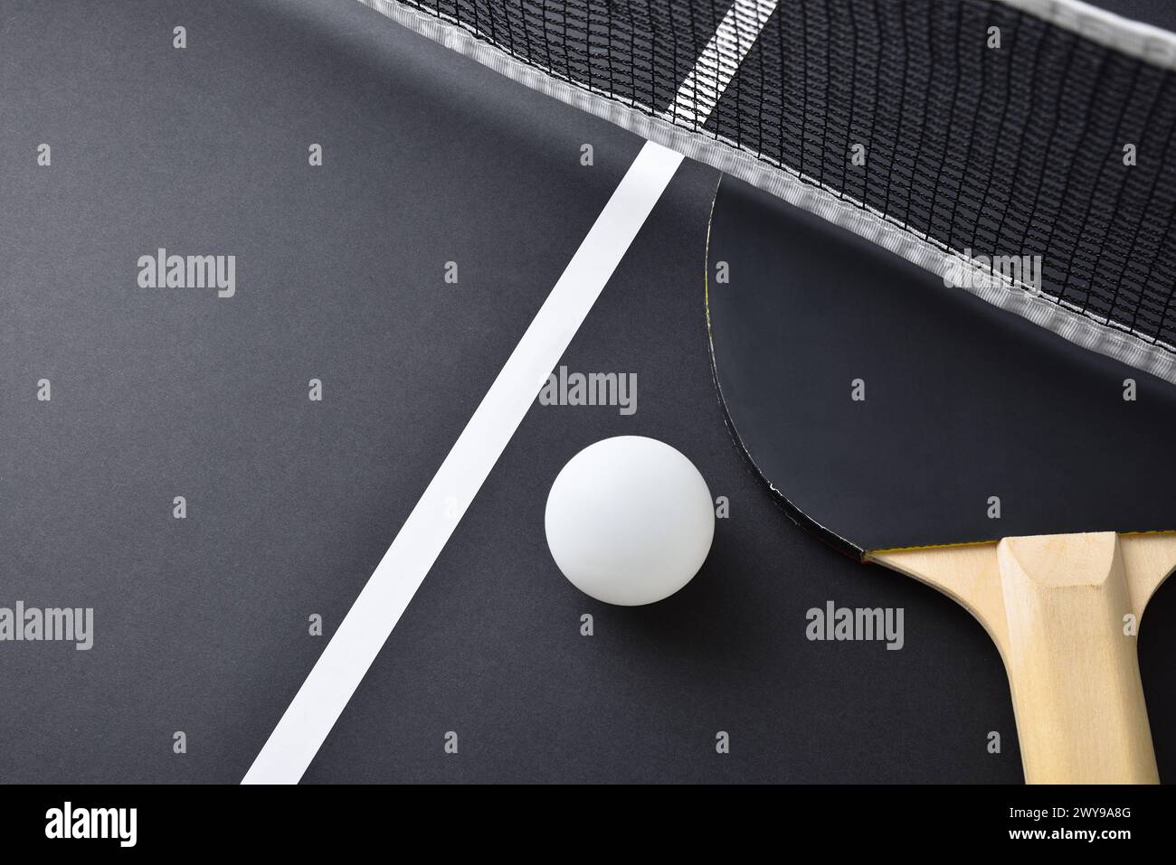 Detail of ping pong paddle with black rubber and white ball on black ...