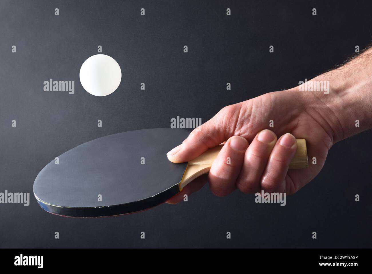 Detail of ping pong player hitting a white ball with the black rubber ...