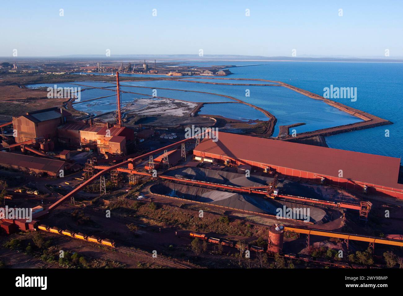 Aerial view of an industrial steel plant with infrastructure and ocean ...