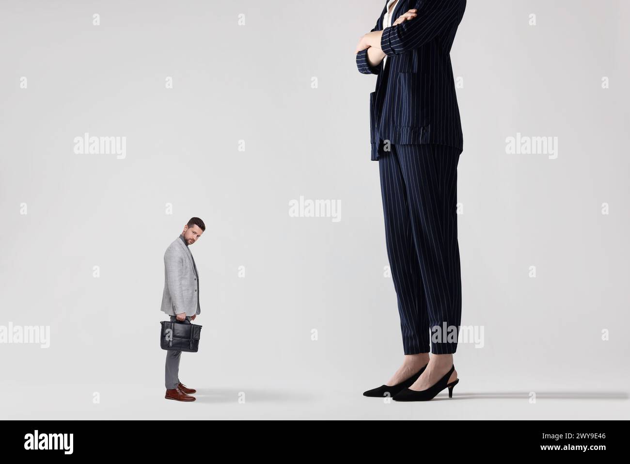 Giant woman and sad small man on light background Stock Photo - Alamy