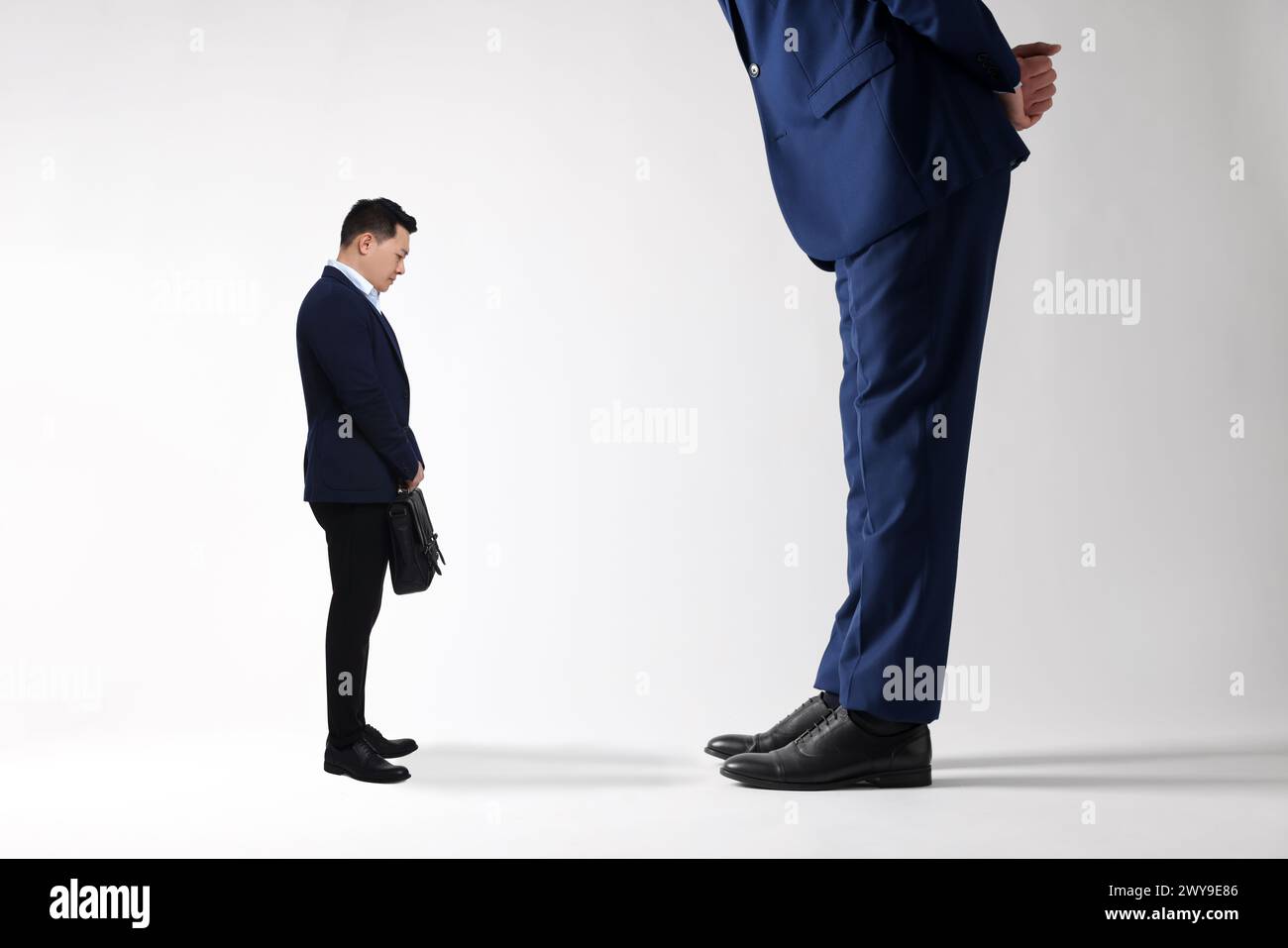 Giant boss and sad small man on light background Stock Photo - Alamy