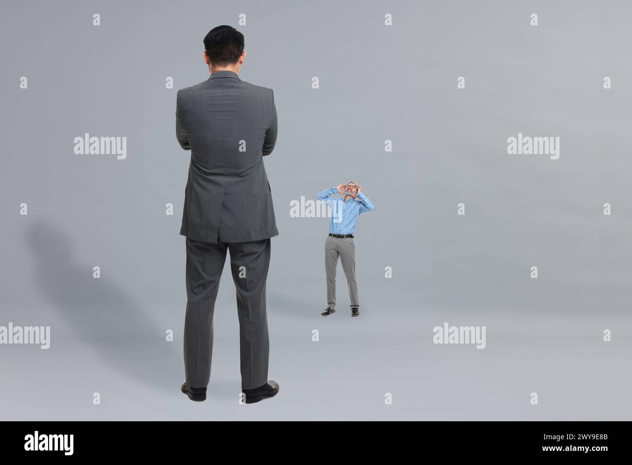 Small man shouting to giant boss on grey background Stock Photo - Alamy