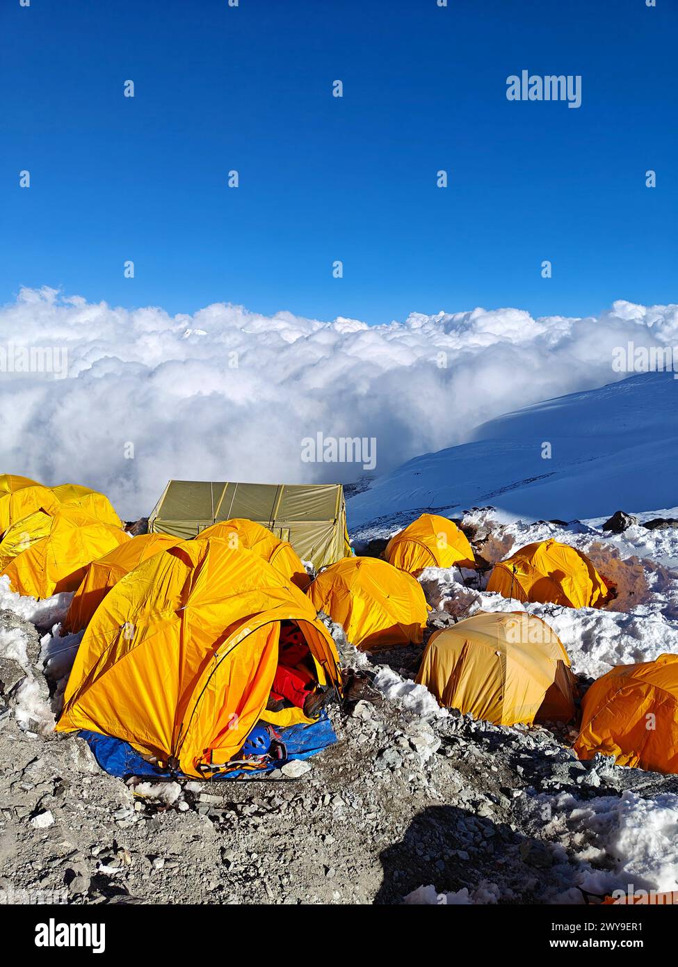 Mountaineering camp on snowy ridge, yellow tents, blue sky, clouds ...