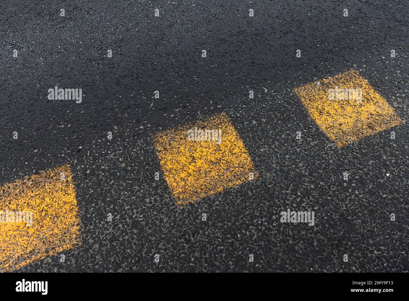 Pedestrian crossing road marking yellow squares on dark tarmac ...