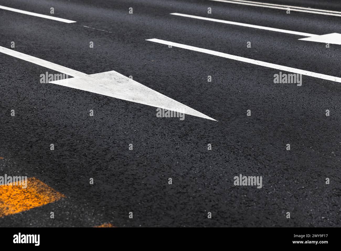 White arrows and lines, road marking on dark highway asphalt. Driving ...
