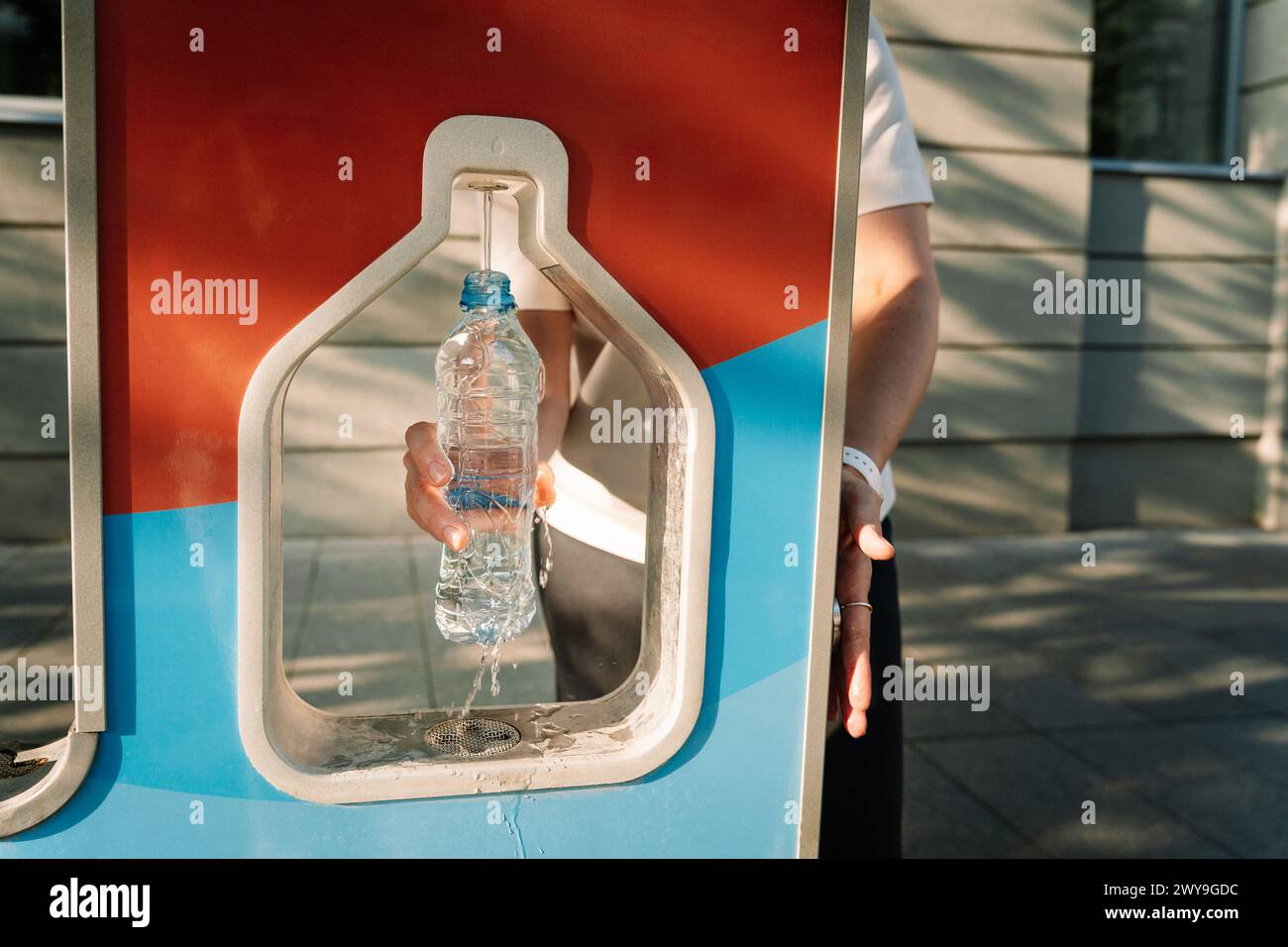 A woman pours clean drinking water into a bottle at a drinking water ...