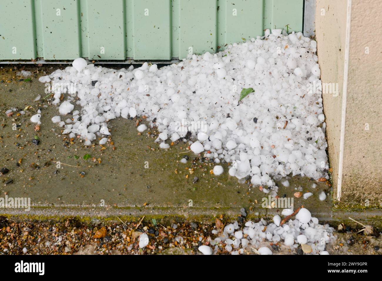 Cluster of hailstones against a garage door and a corner of a wall ...