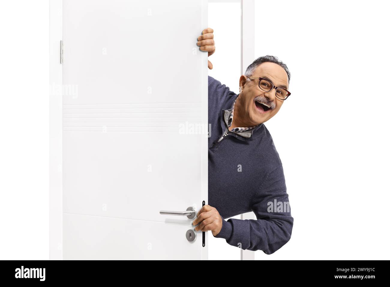 Cheerful mature man peeking from behind a white door isolated on white ...