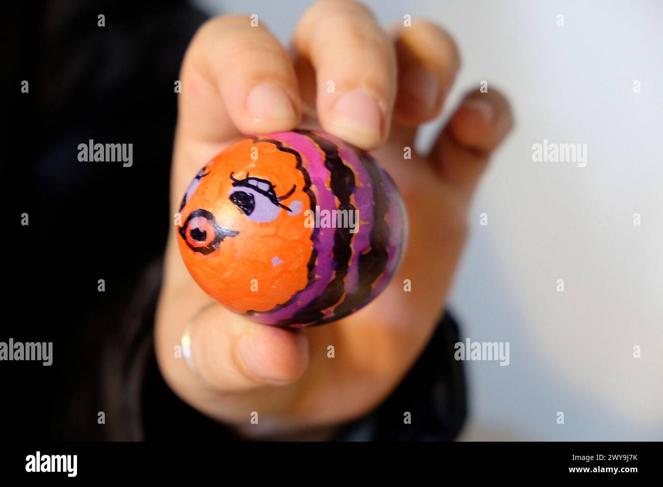Hand holding a painted hard boiled egg with the face of a fish for use ...