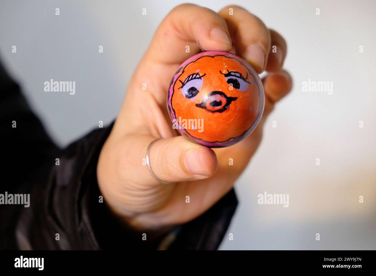 Hand holding a painted hard boiled egg with the face of a fish for use ...