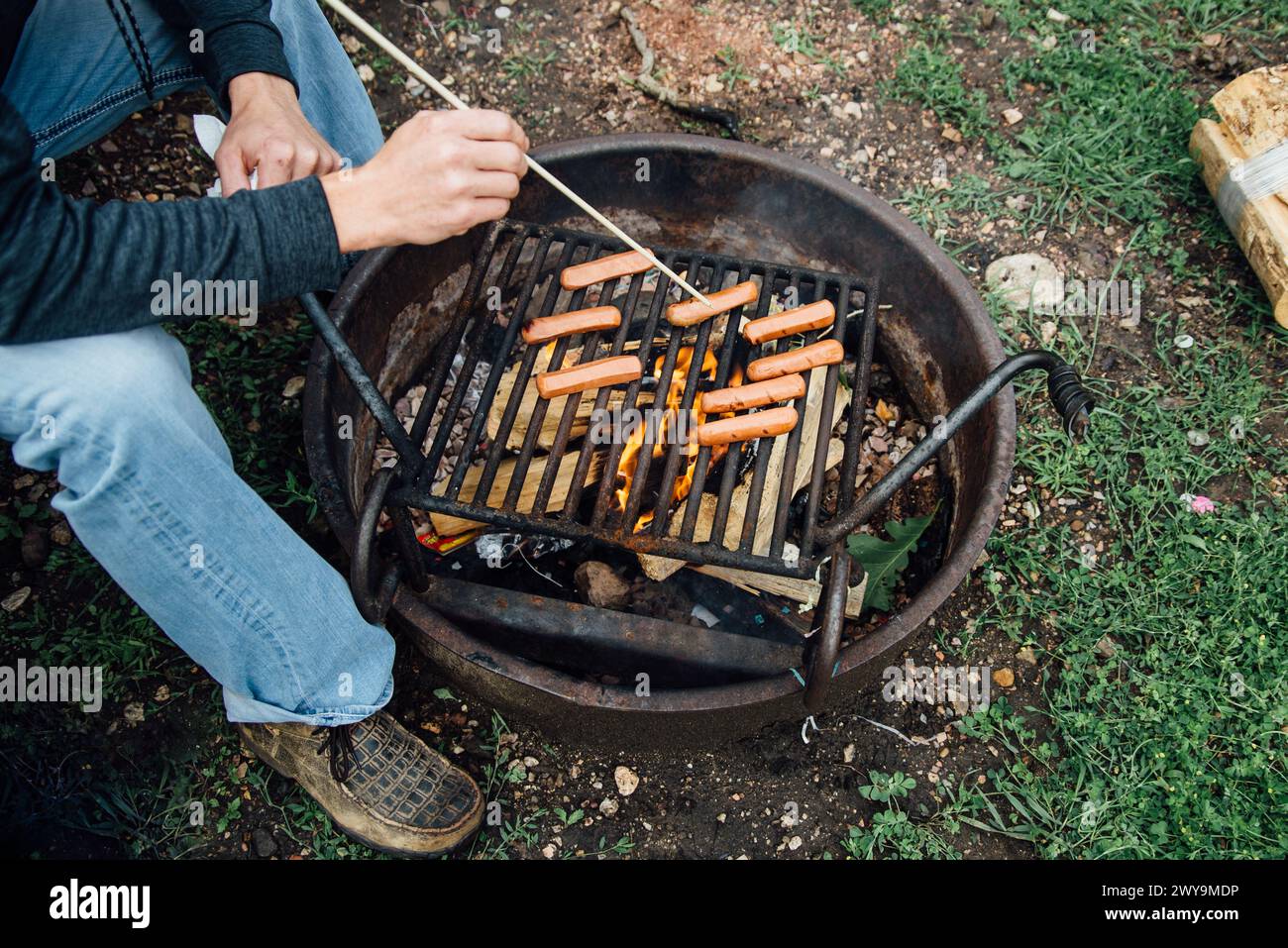 Overhead view of man cooking hot dogs over fire on summer afternoon ...