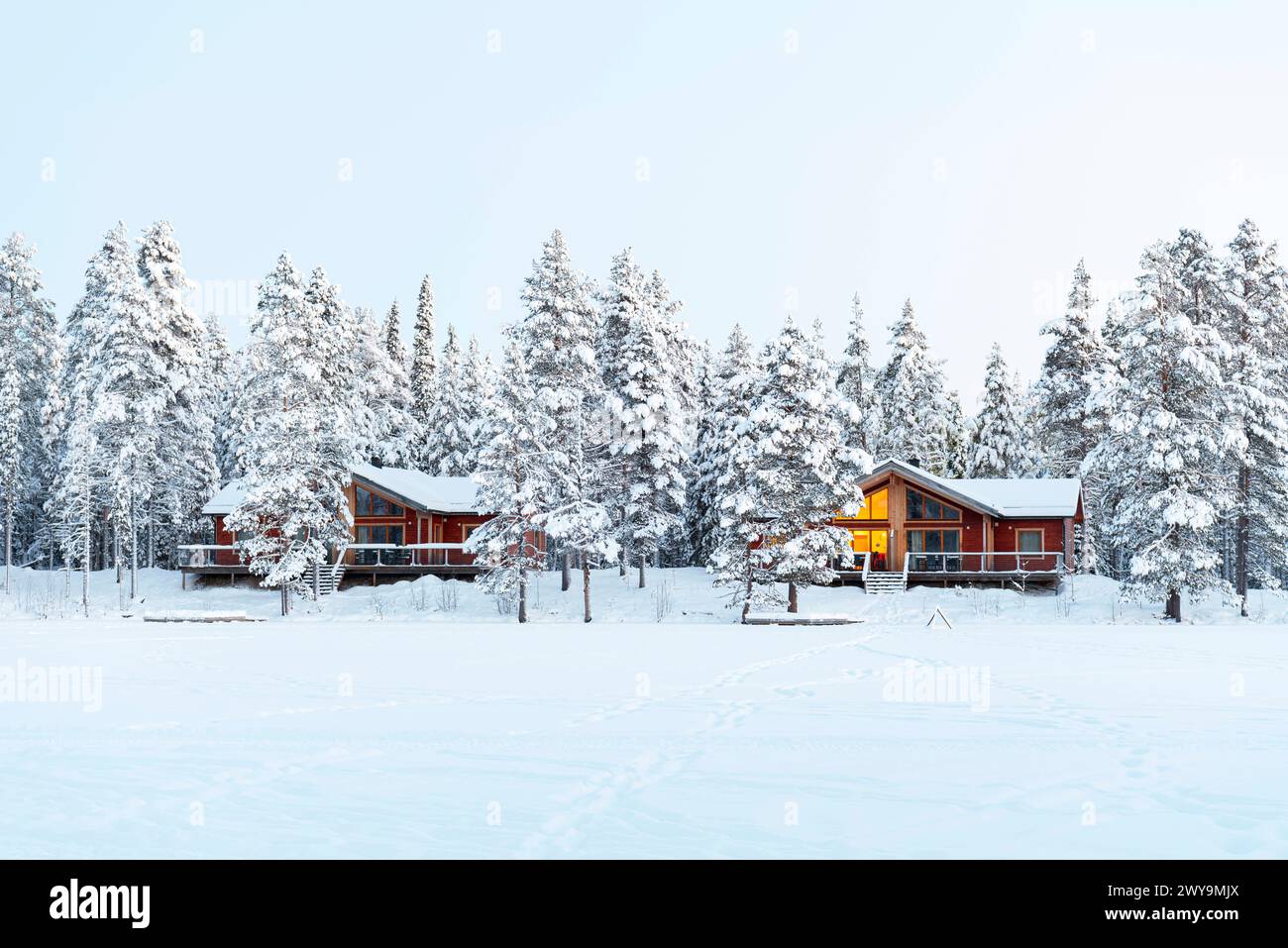 Winter view of a mountain lodge surrounded by frozen forest covered ...