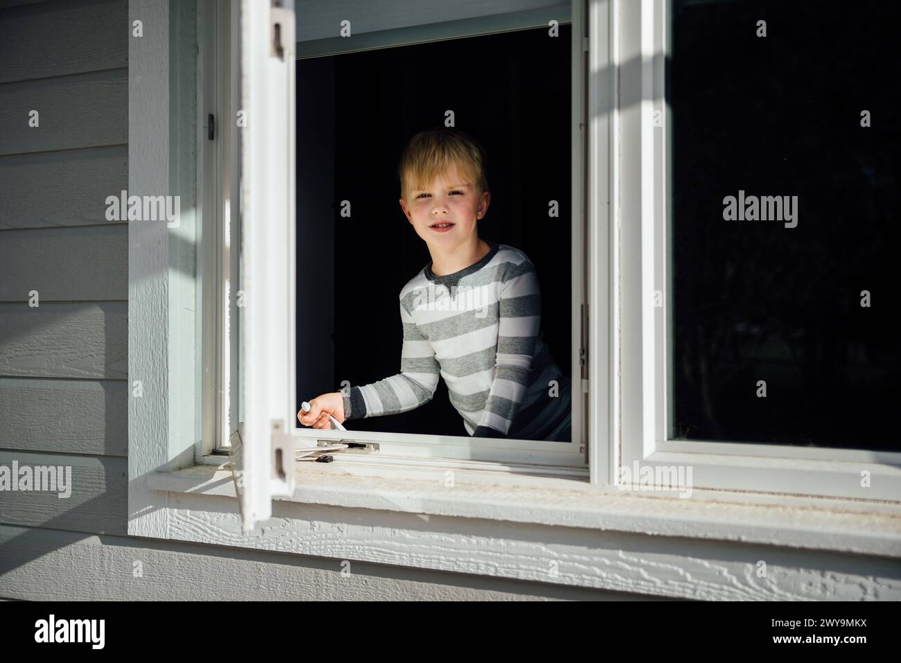 Portrait of young boy opening window while looking outside Stock Photo ...