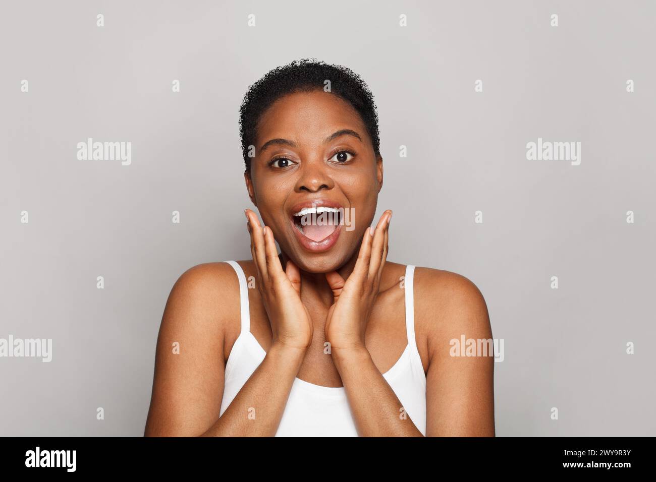 Surprised healthy lady with dark clean fresh skin on white background ...