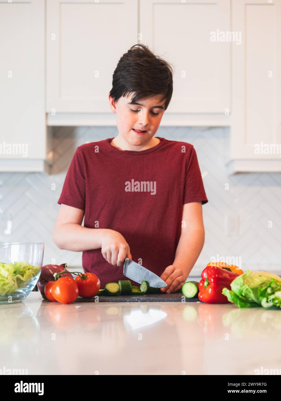 Teen boy chopping vegetables for salad in white kitchen Stock Photo - Alamy