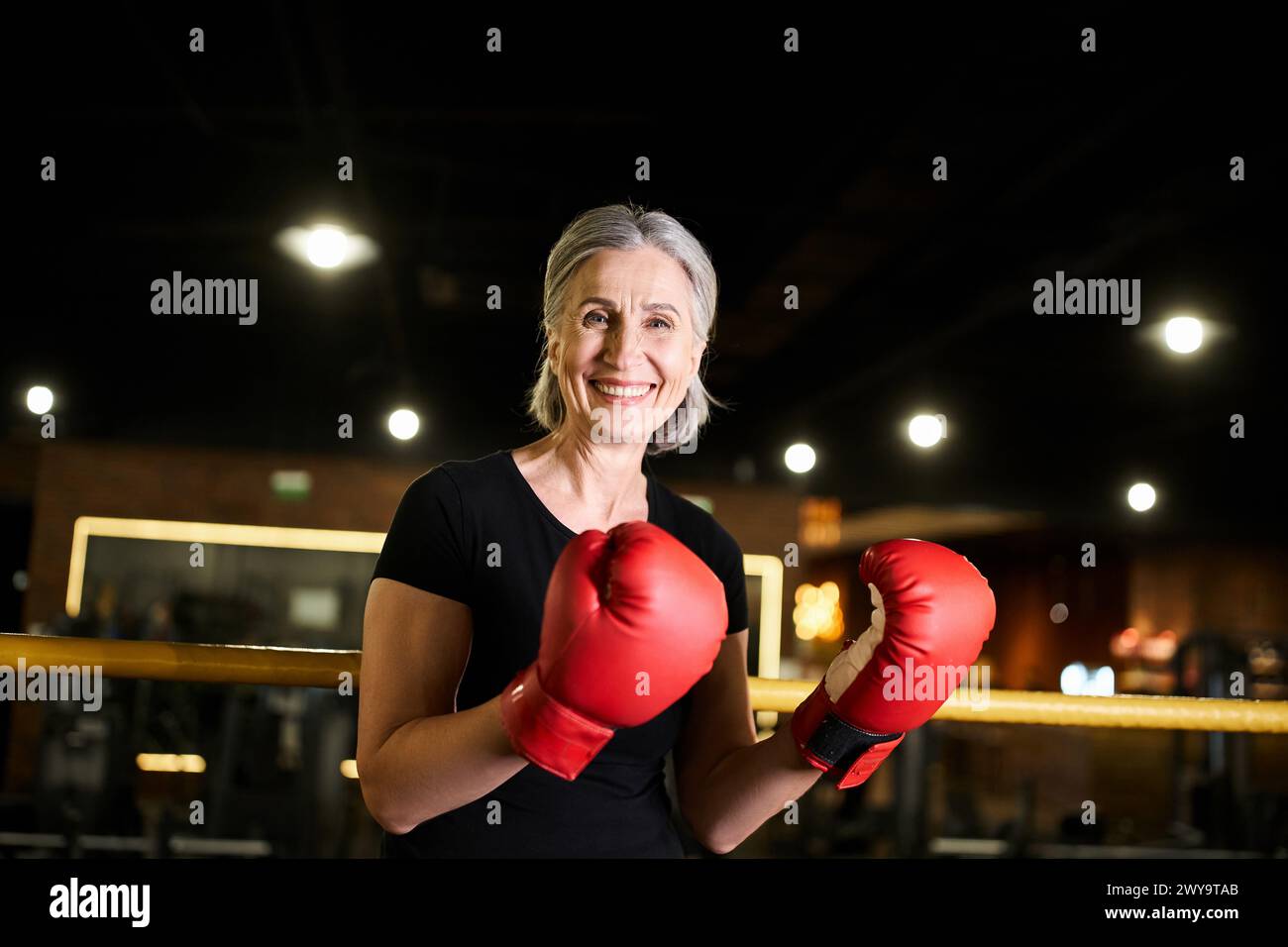 appealing jolly mature woman in sportswear with boxing gloves training ...