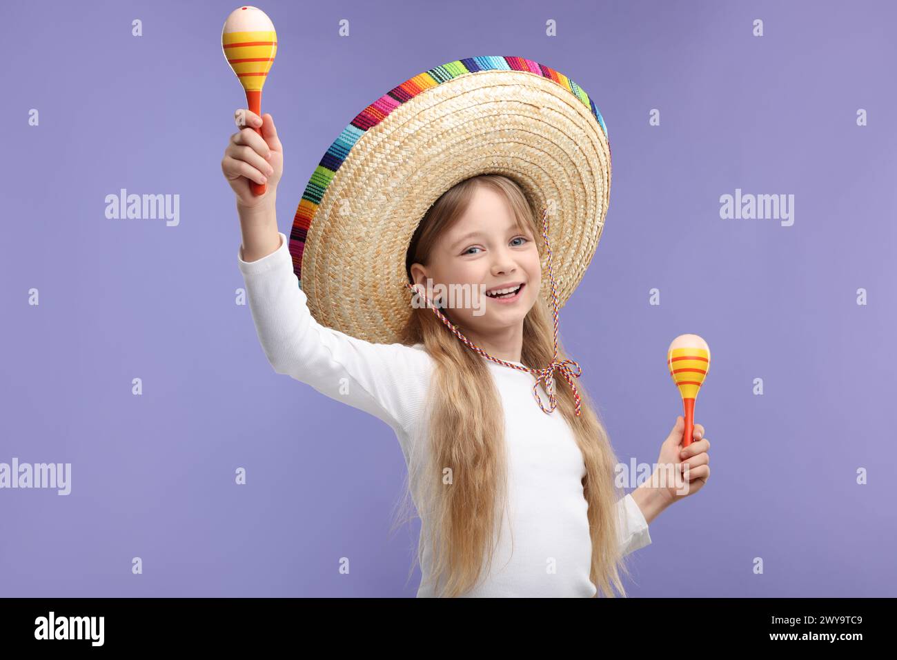 Cute girl in Mexican sombrero hat dancing with maracas on purple ...