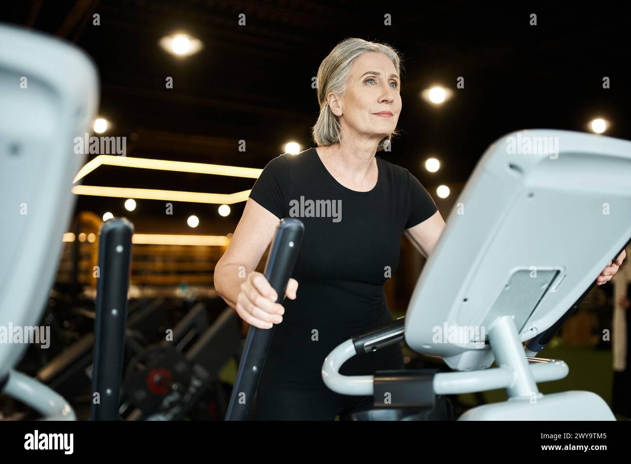 good looking jolly mature sportswoman in black t shirt exercising ...