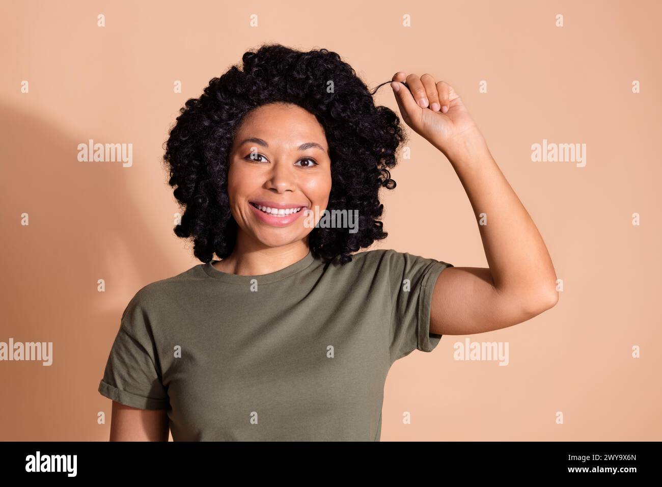 Portrait of funky positive person with perming coiffure dressed khaki t-shirt hand hold curl ...