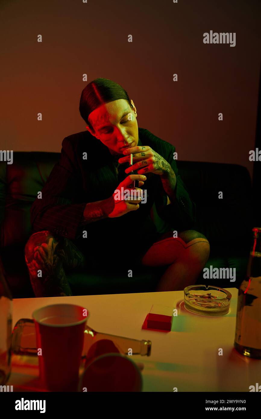 A man sitting on a couch smoking a cigarette Stock Photo - Alamy