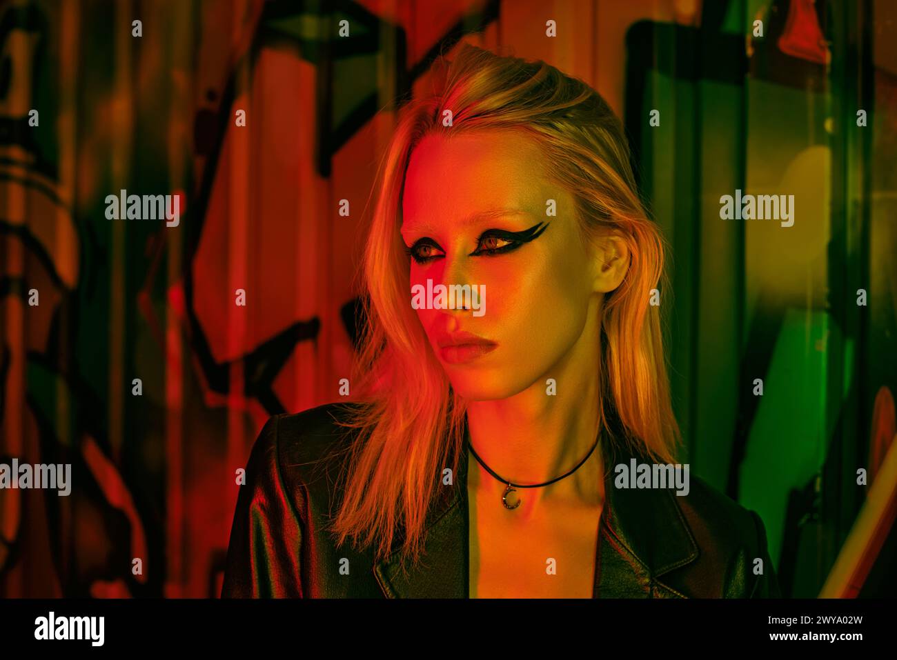 Woman wearing black leather jacket standing amongst red and green ...